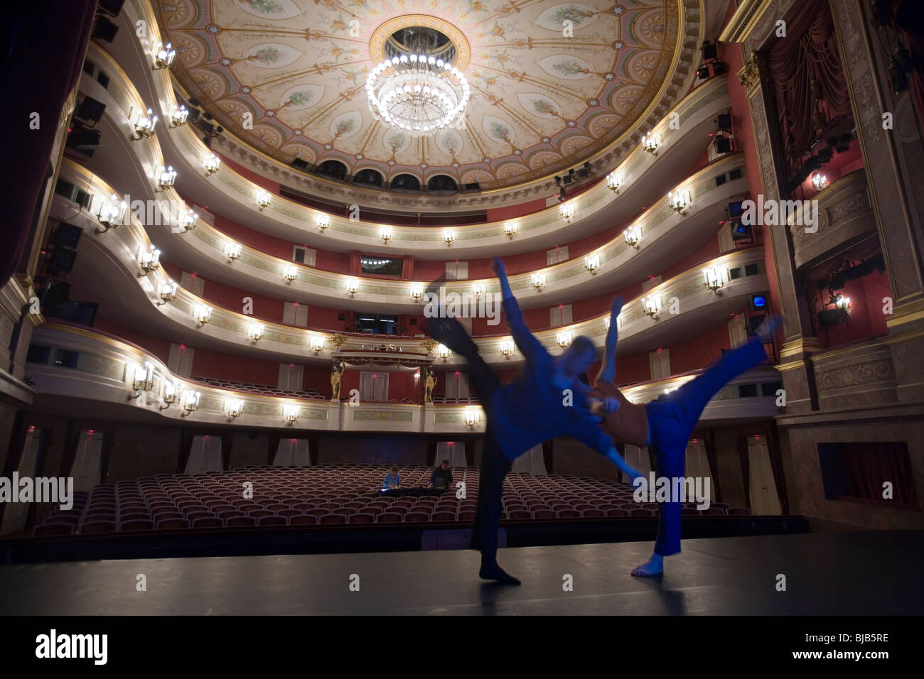 Two dancers lit in blue rehearsing on the stage of a theater. Munich ...