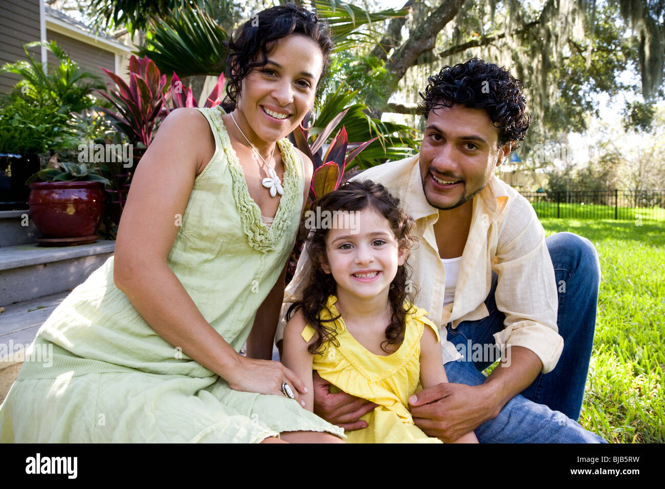 Hispanic family with little girl sitting together in backyard Stock ...