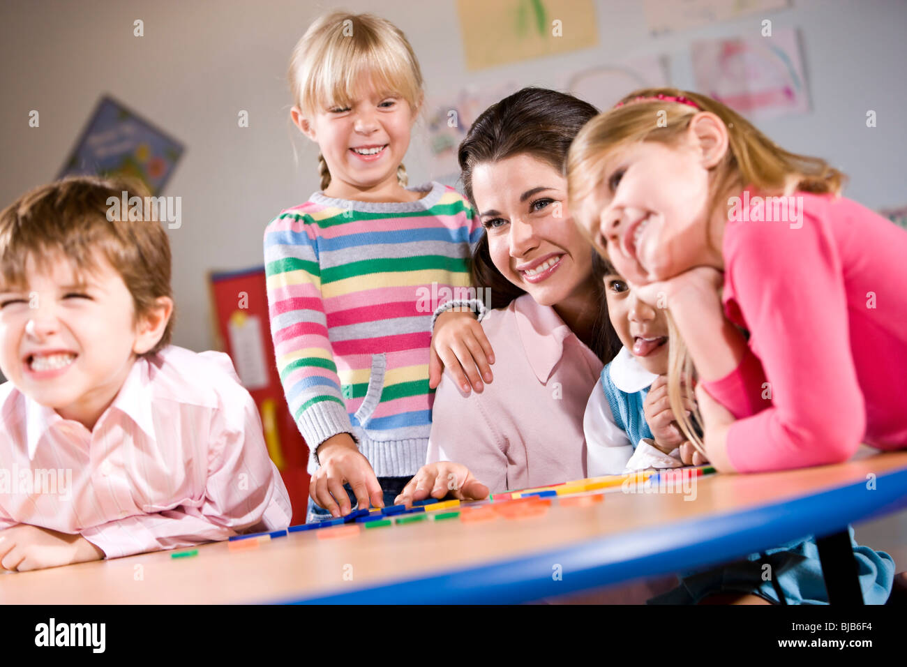 Teacher with preschool children smiling in classroom Stock Photo - Alamy