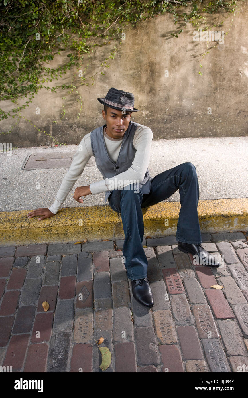 Handsome stylish young African-American man sitting on curb Stock Photo ...