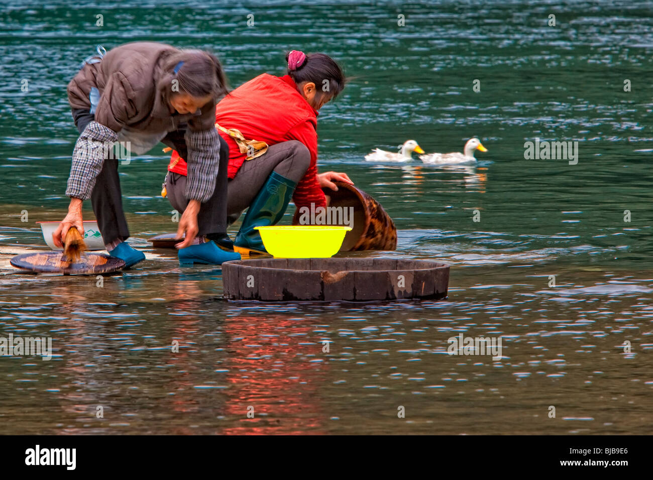 Two women are washing at the bank of a river Stock Photo - Alamy