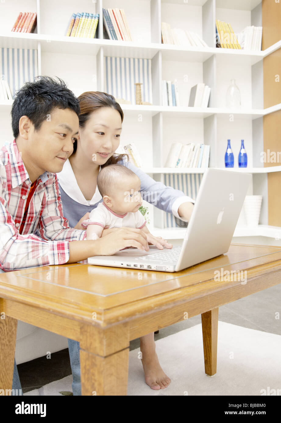 Parents and child looking at laptop Stock Photo - Alamy