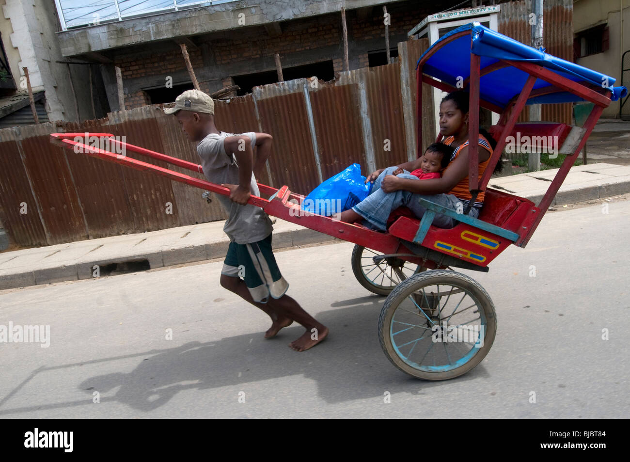 Rickshaw puller with woman passenger and young child Stock Photo - Alamy