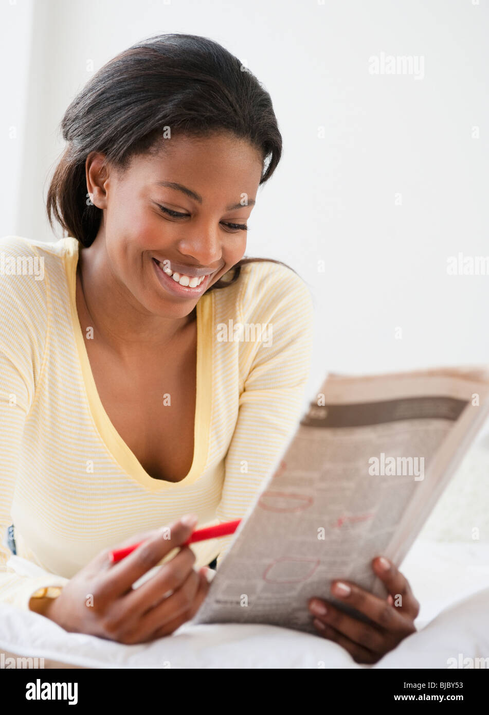 Mixed race woman reading classified ads Stock Photo - Alamy