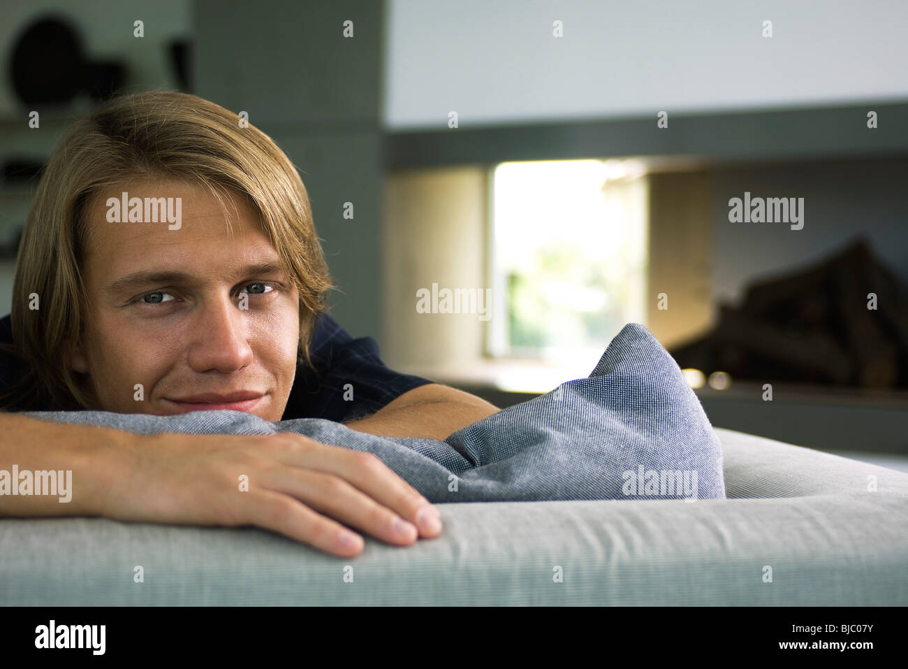 Man relaxing on sofa, smiling, portrait Stock Photo - Alamy