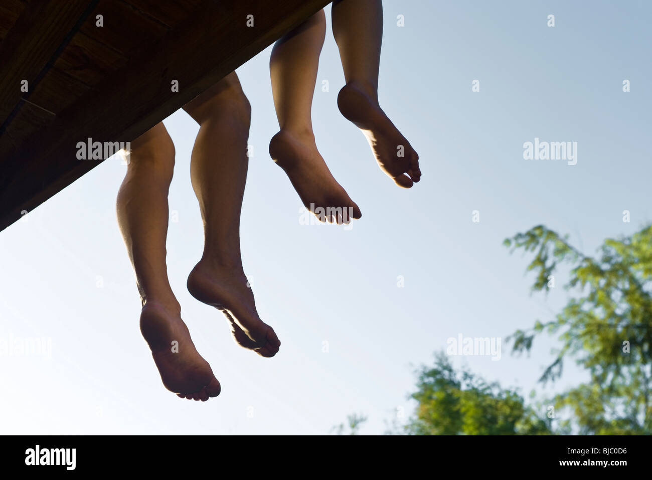 Adult and child sitting on deck with legs dangling off edge, cropped ...