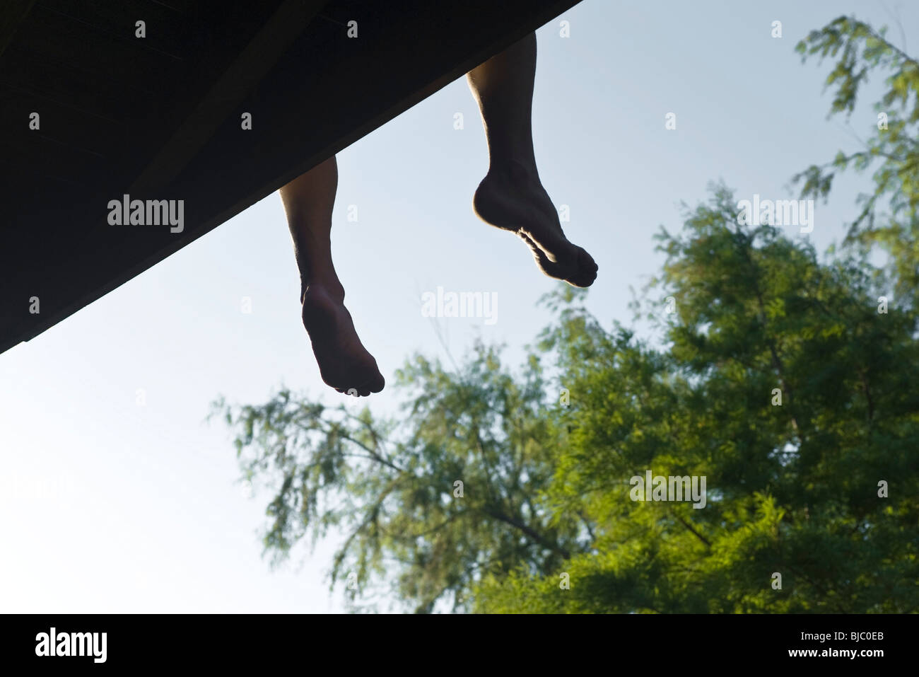 Person sitting on deck, dangling feet over edge, cropped Stock Photo ...
