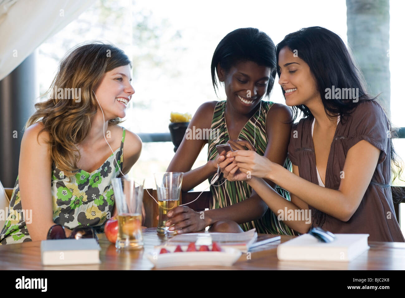 Friends sharing earphones listening to music together Stock Photo - Alamy