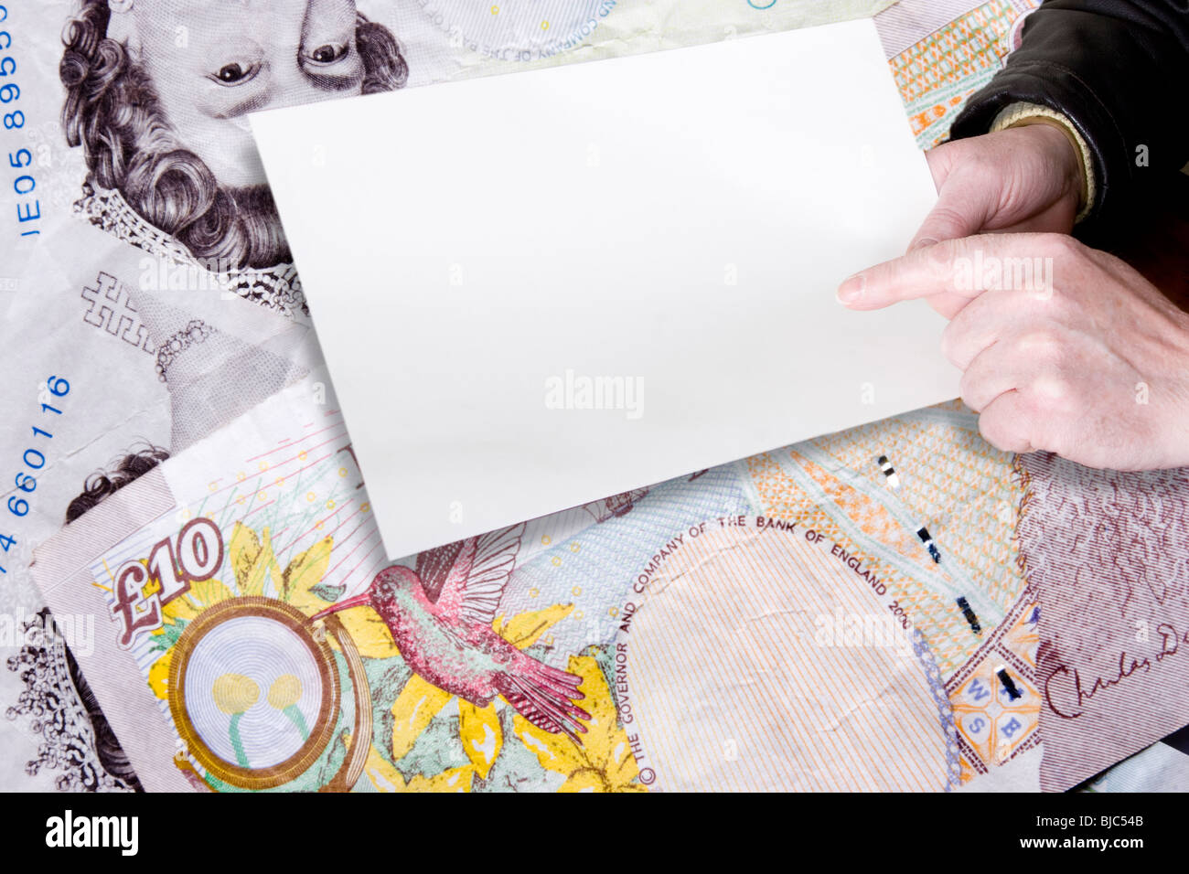Person passing a letter over a pile of money Stock Photo - Alamy