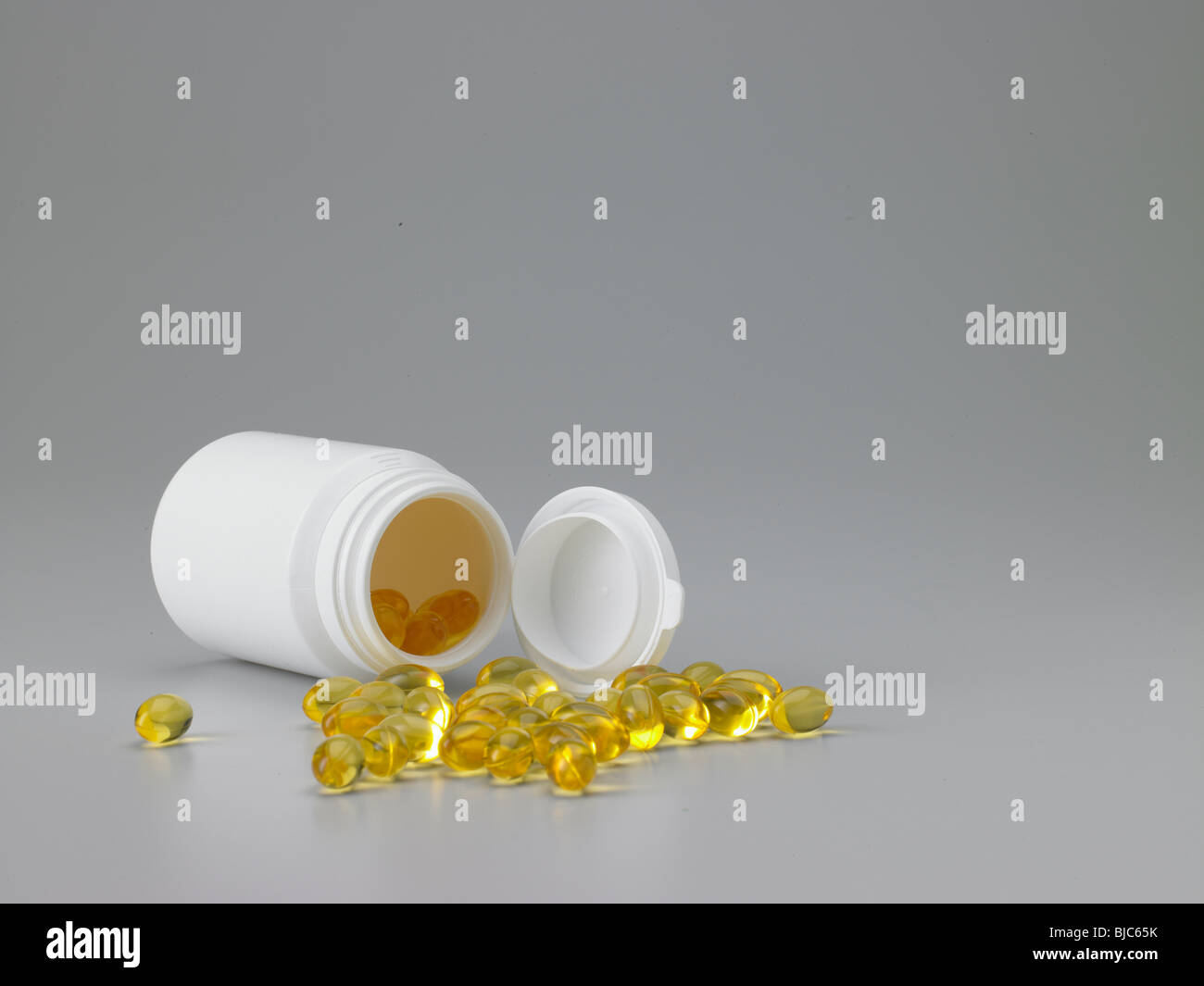 Yellow medical capsules spilling from one container. Landscape.. Low ...