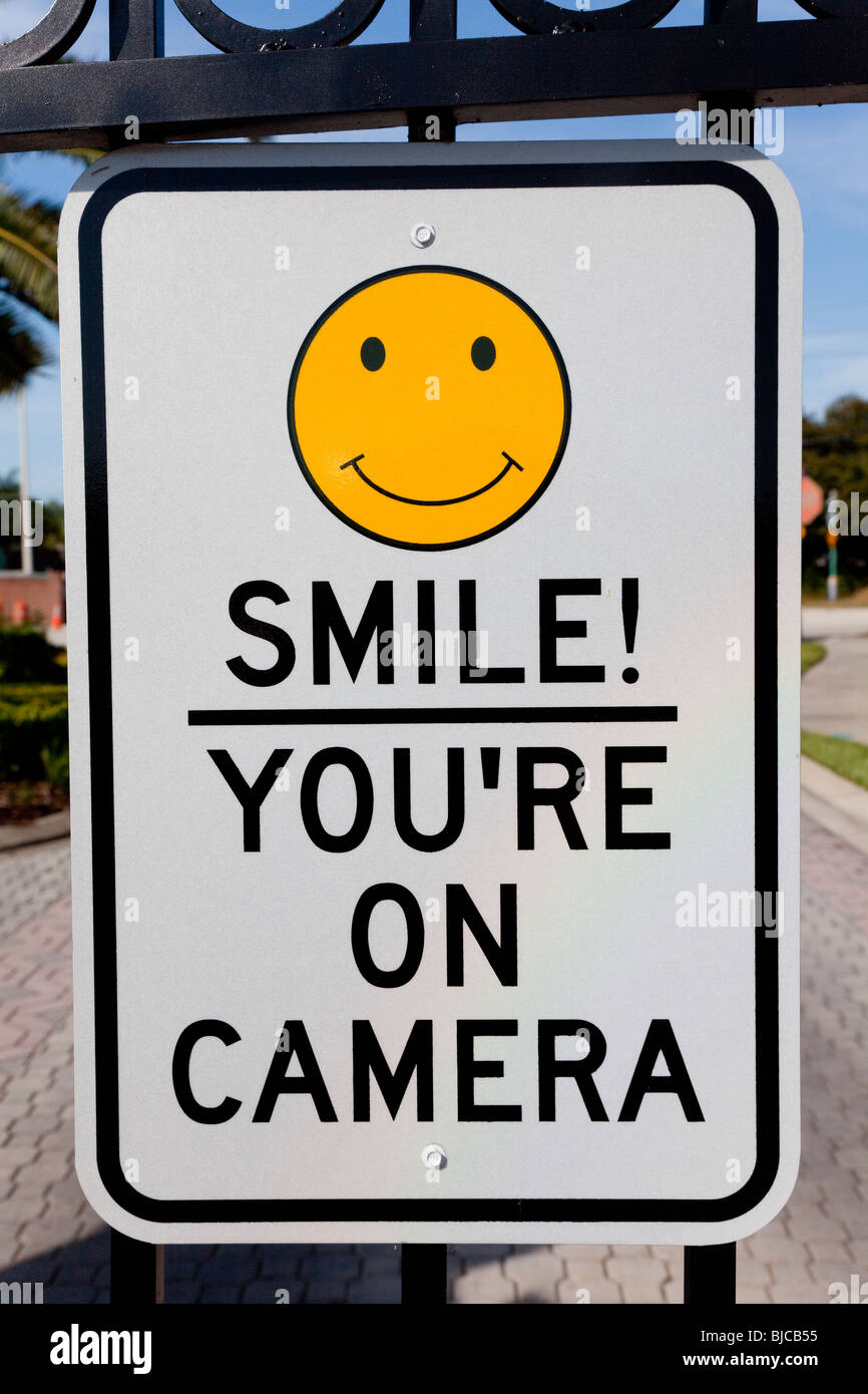 A Smile You're on Camera sign affixed to security gates Stock Photo - Alamy