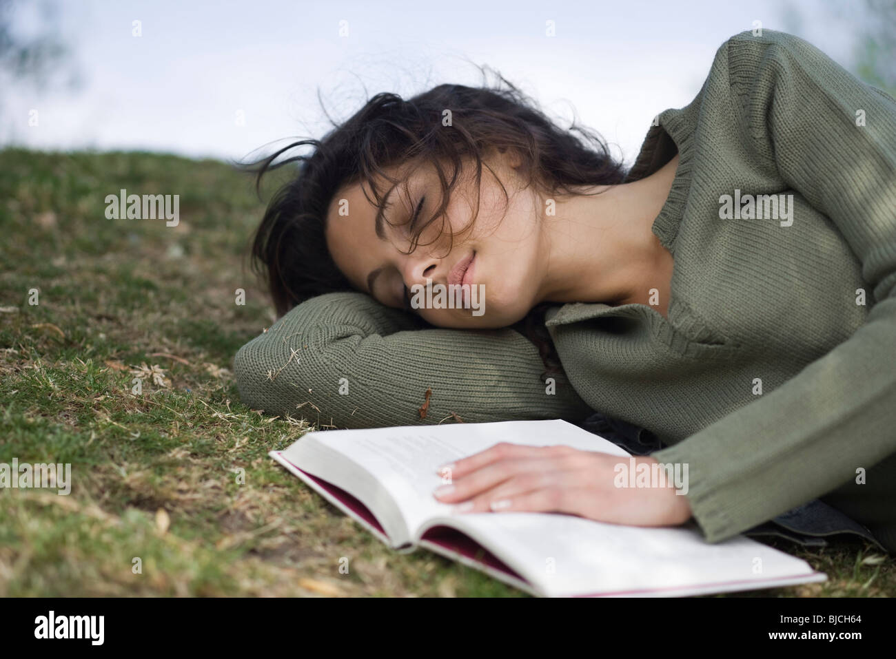 Young woman napping on ground with book Stock Photo - Alamy
