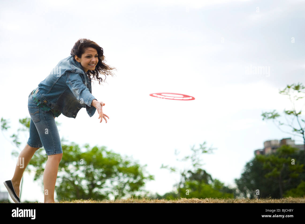 Woman throwing flying disc at park Stock Photo - Alamy