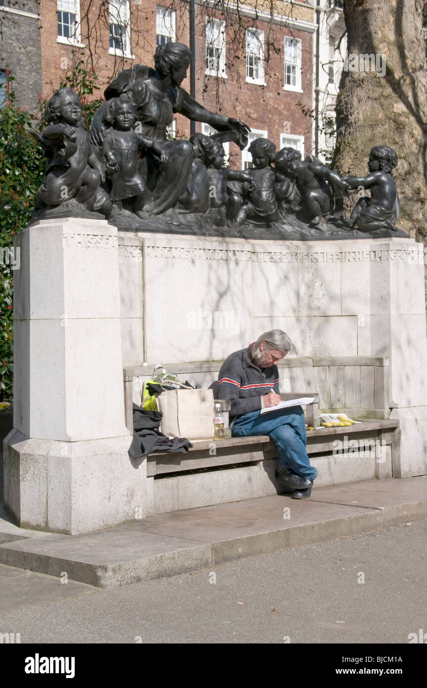 UK Homeless man reading at a bench in Lincolns Inn London Stock Photo ...