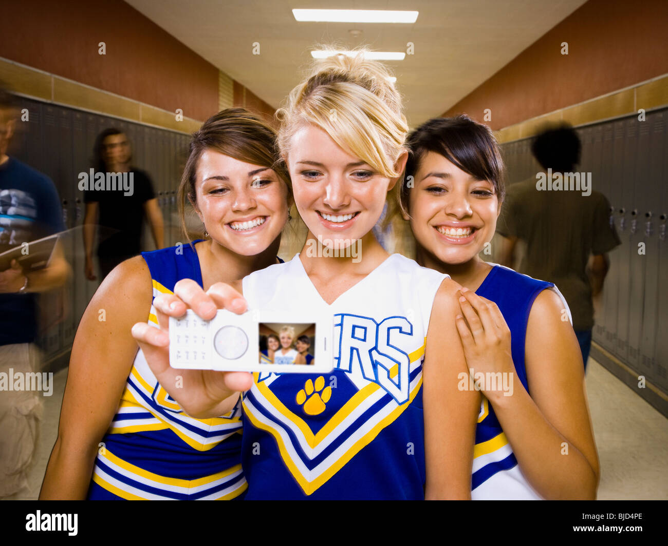 Three High School cheer leaders taking a picture with a mobile phone ...
