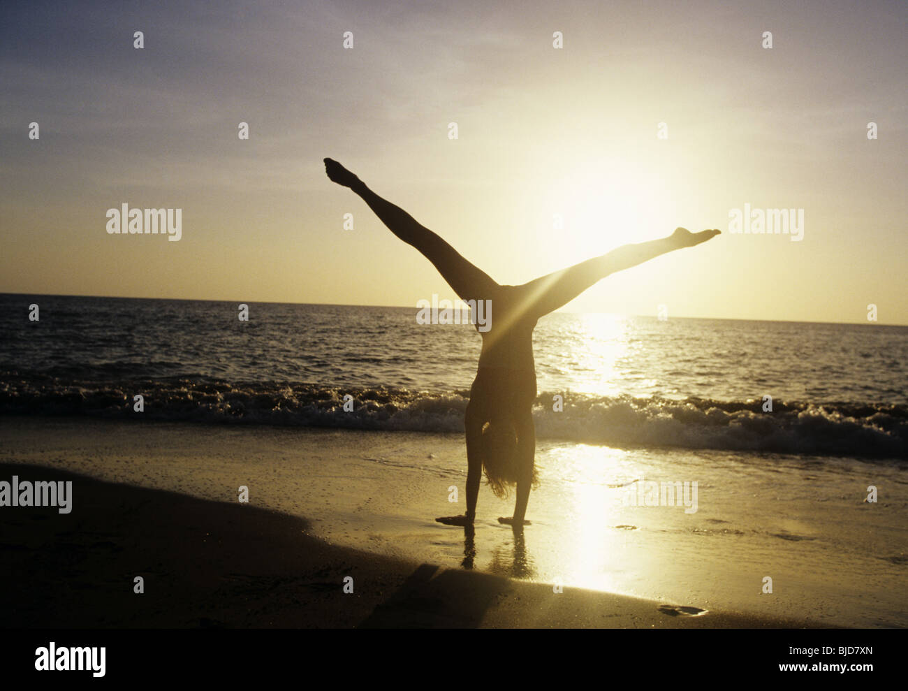 Woman does handstand on beach at sunset Stock Photo - Alamy