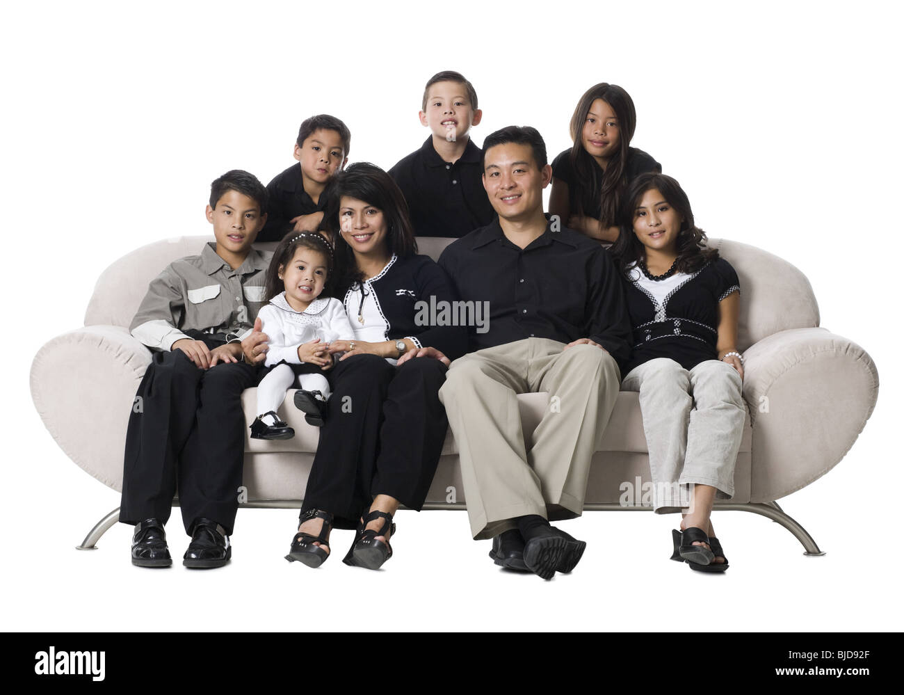 Family sitting on a couch smiling Stock Photo - Alamy