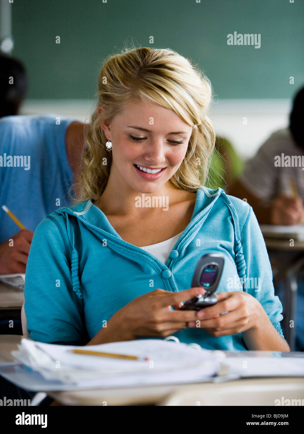 Girl looking at mobile phone in class Stock Photo - Alamy