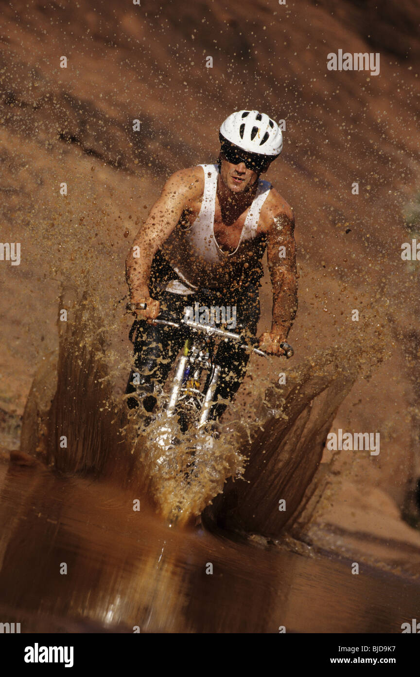 Dirt bike racer in action as he cycles through muddy water splash Stock ...
