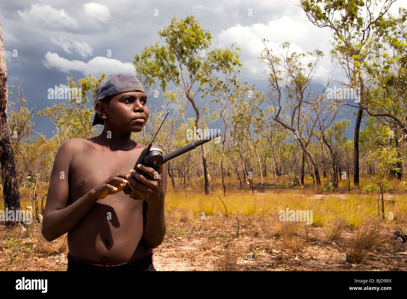 Aboriginal boy Mitchell using a stat phone as a storm approaches Gamedi ...