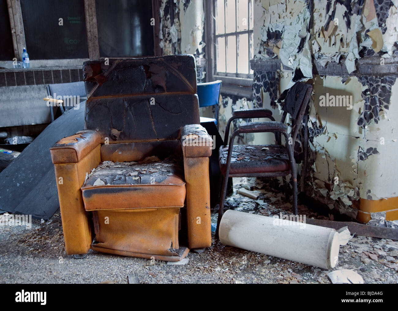 Fire damaged chair in burnt out common room in abandoned mental asylum ...