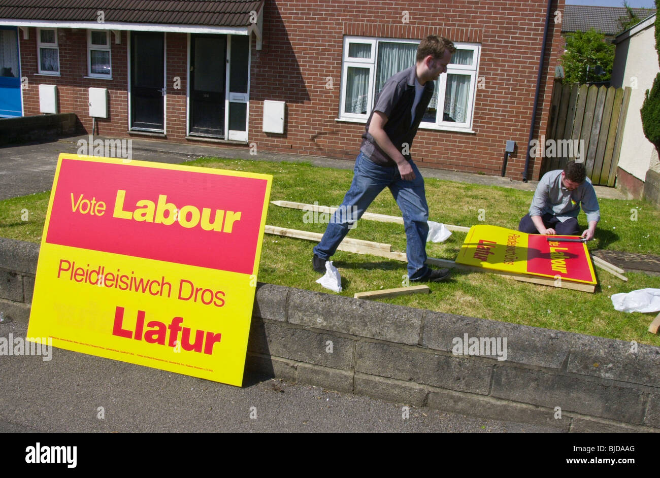 Labour Party workers erect bilingual Welsh English VOTE LABOUR signs ...