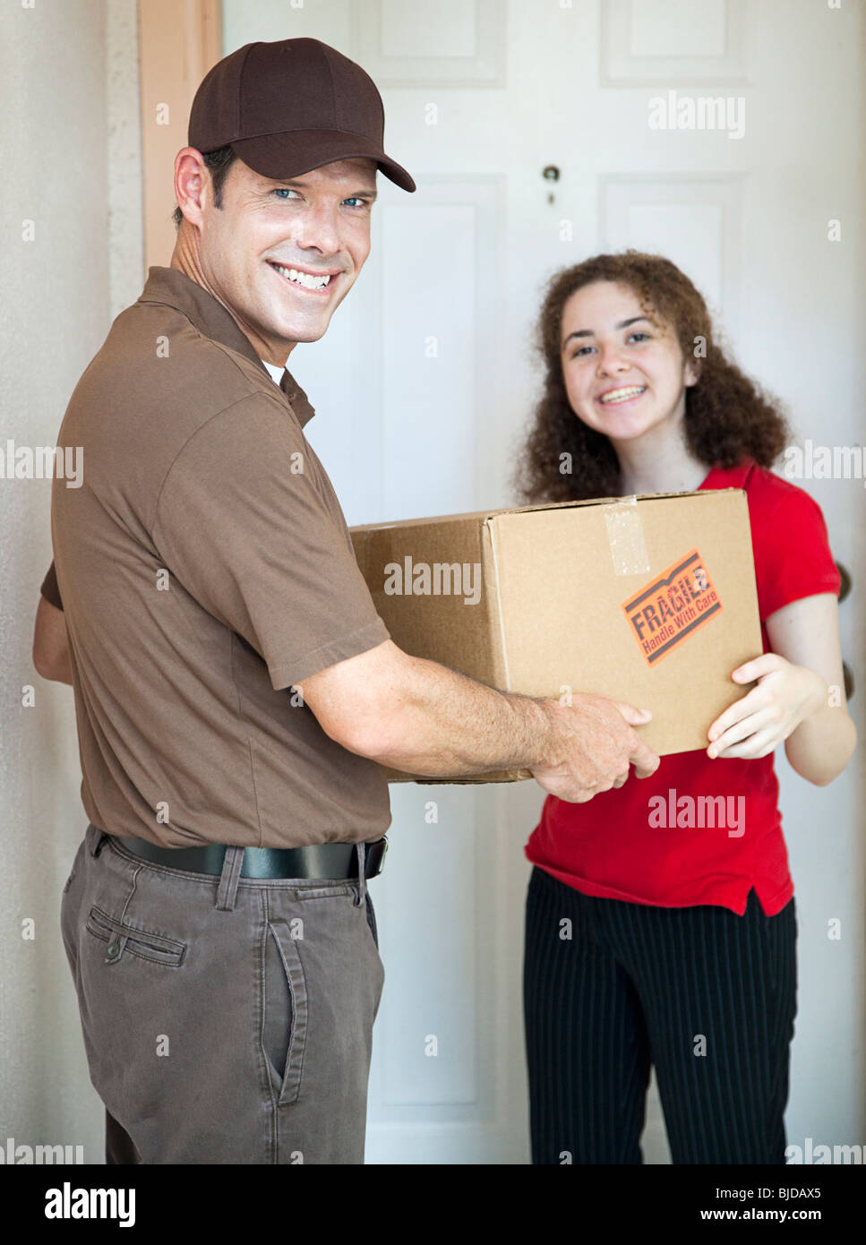Handsome delivery man smiles as he delivers a package to a customer ...