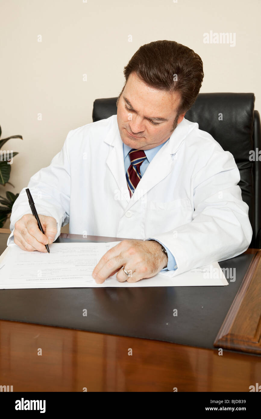 Doctor at his desk writing in a patient's chart Stock Photo - Alamy