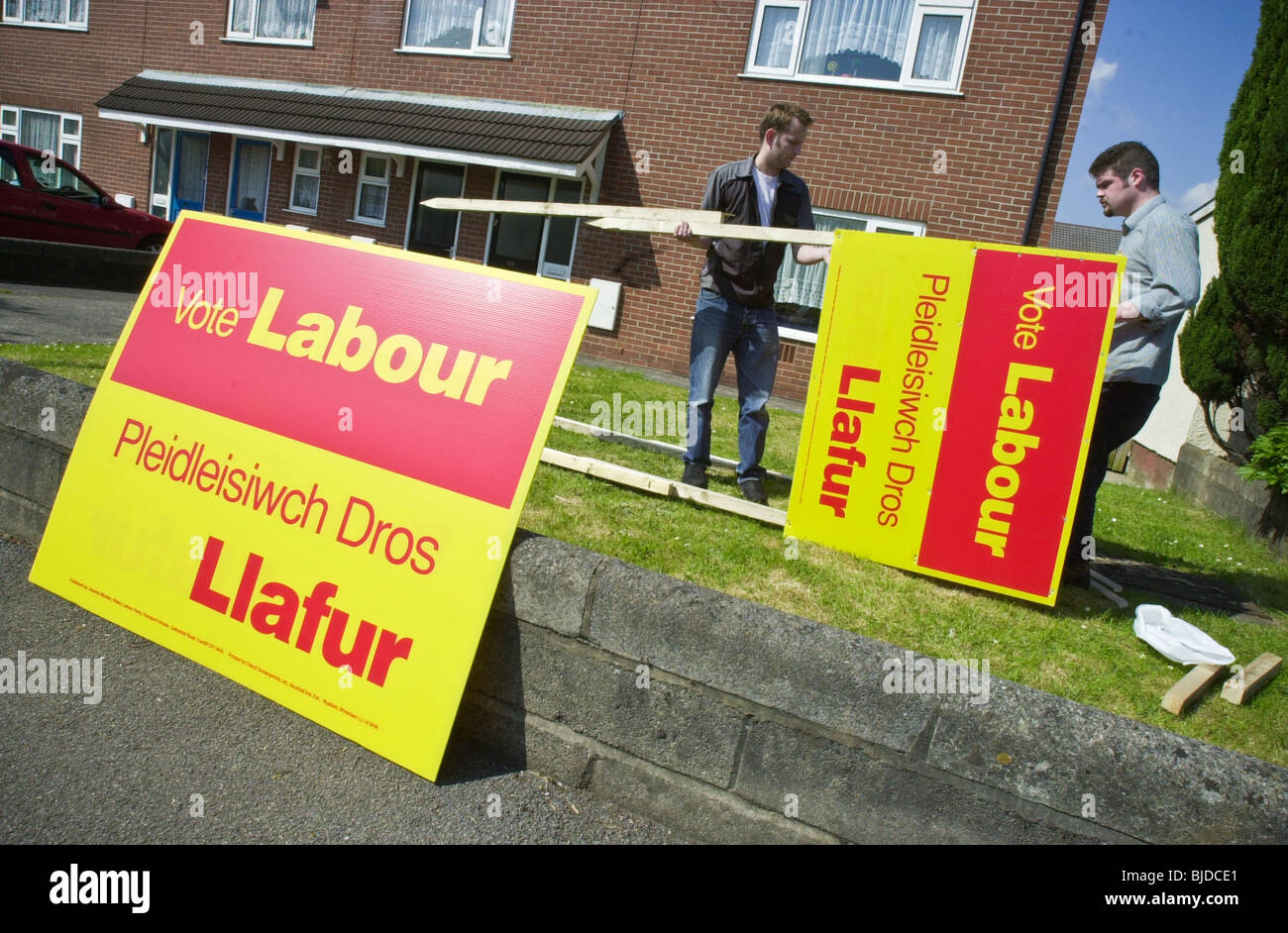 Labour Party workers erect bilingual Welsh English VOTE LABOUR signs ...