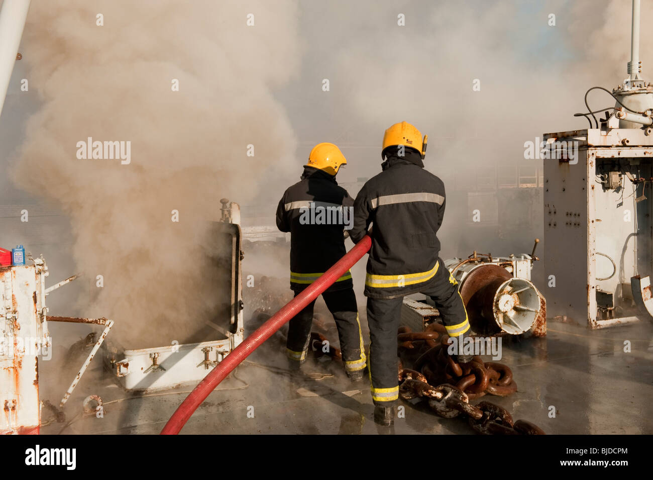 Firemen tackle fire in hold of ship with thick smoke Stock Photo - Alamy