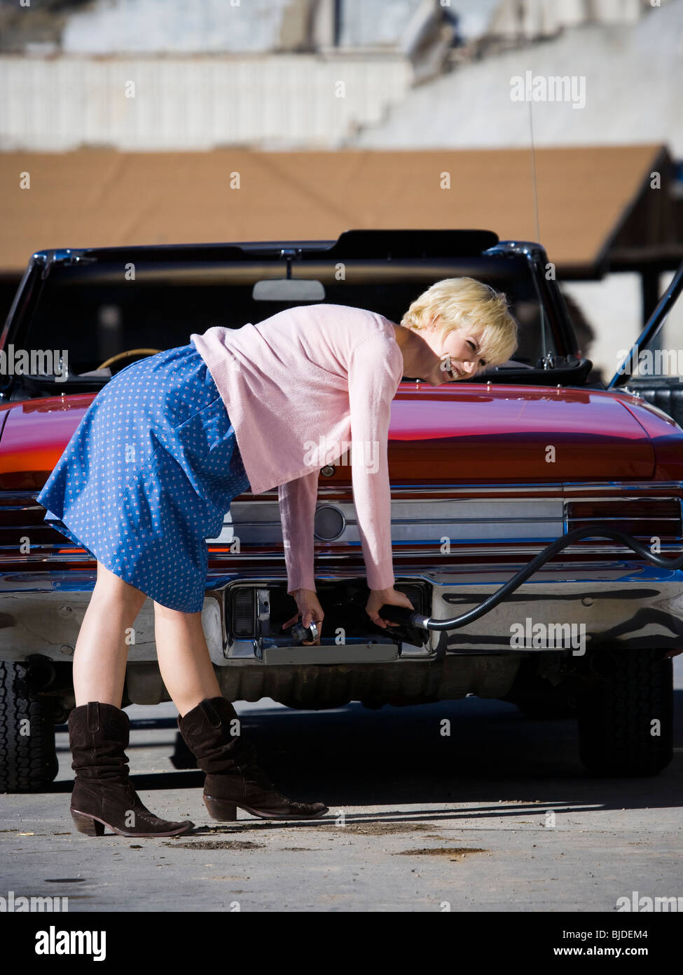 Young woman pumping gas into vintage convertible Stock Photo - Alamy