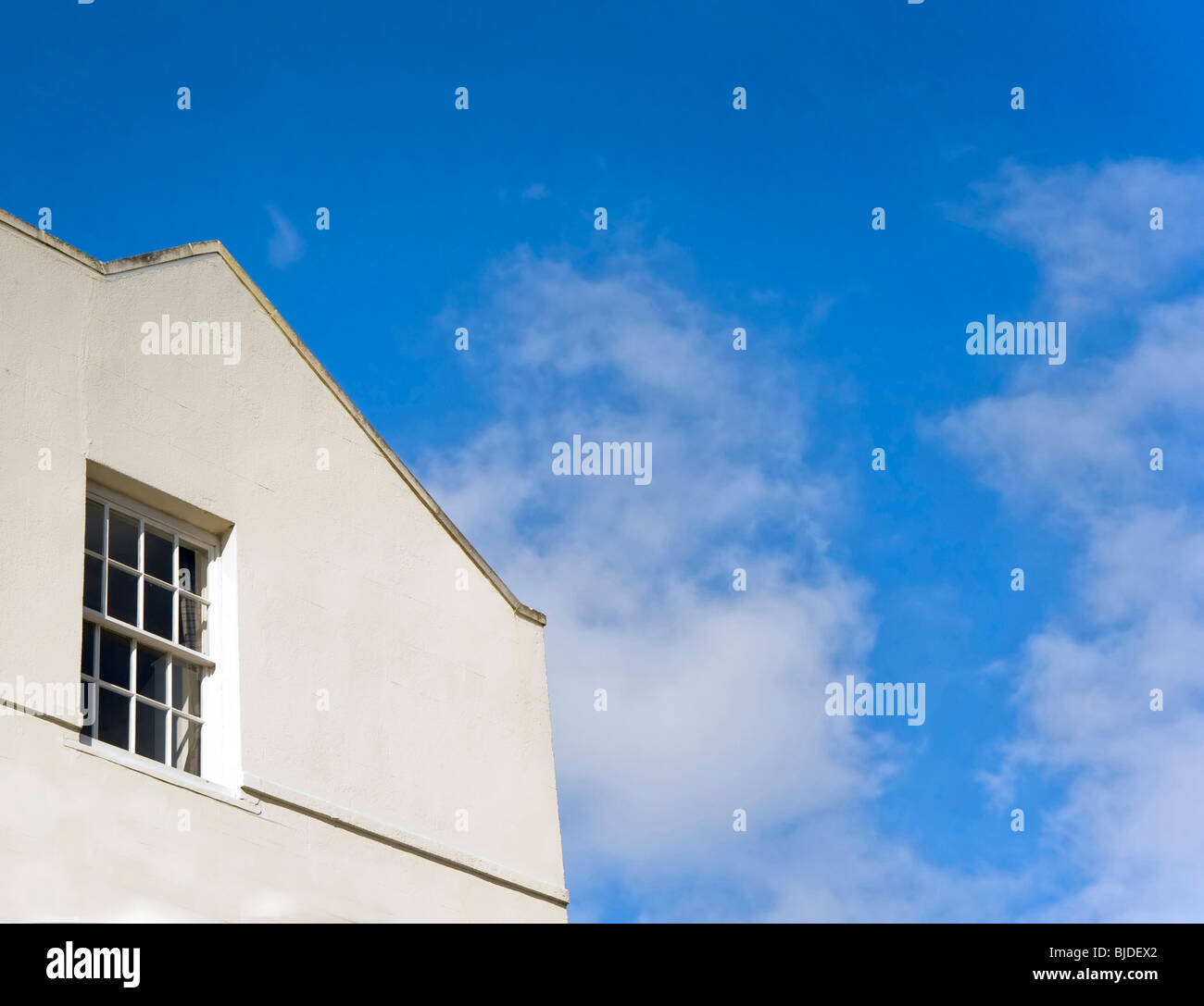 white building with diagonal roof against vivid blue sky with clouds ...