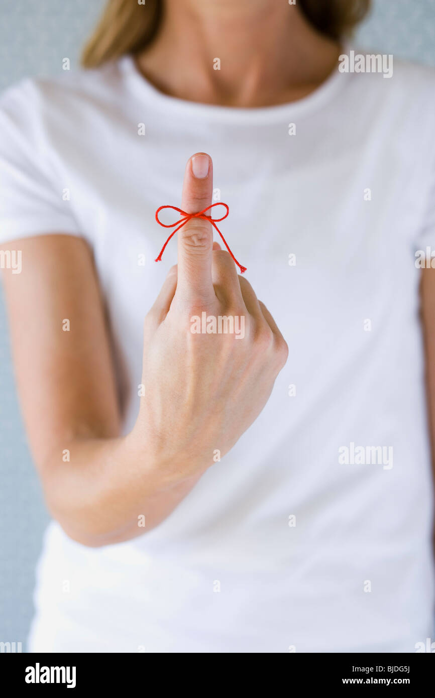 Woman with a red string tied on her finger Stock Photo - Alamy