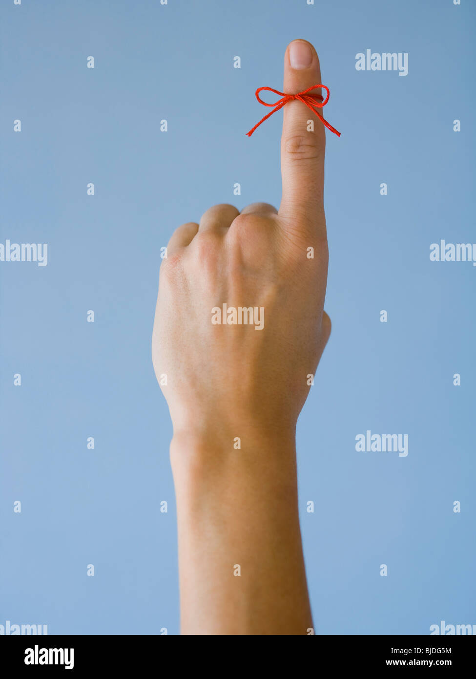 Woman with a red string tied on her finger Stock Photo - Alamy