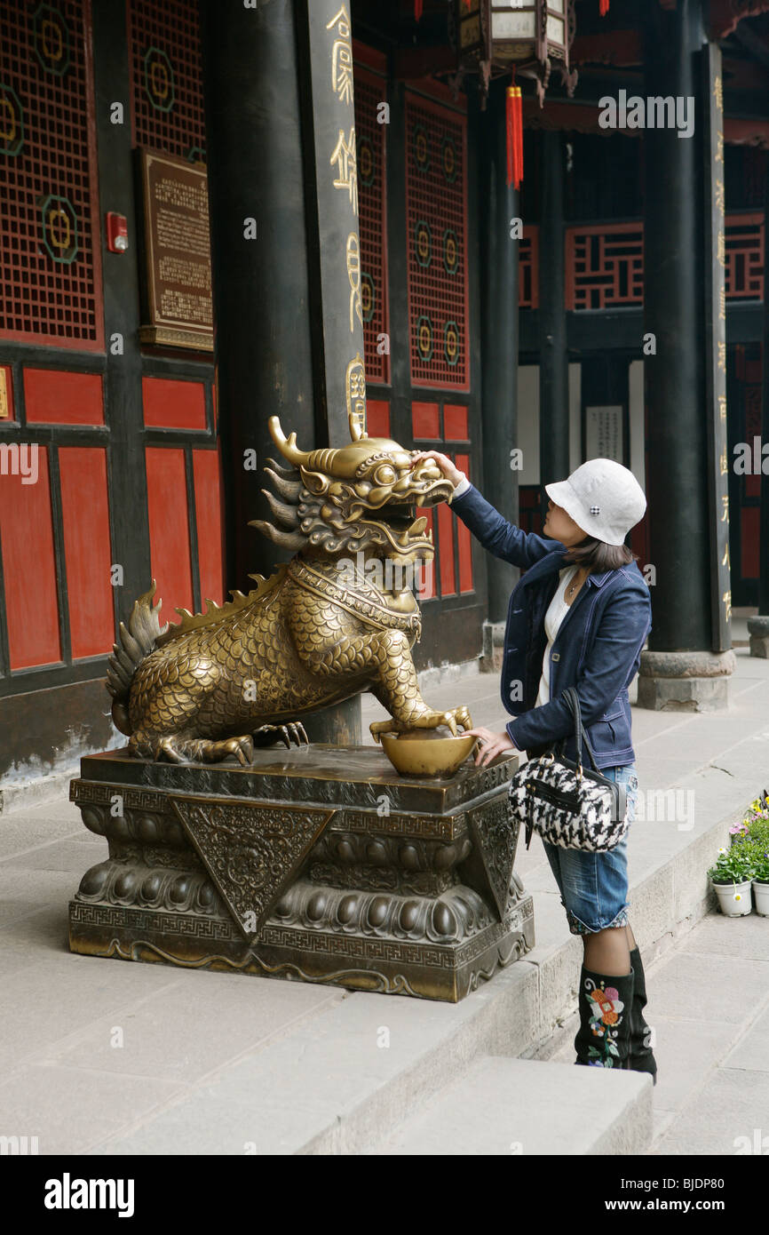 Woman touching a golden dragon statue at (Buddhist) Wenshu Temple in ...