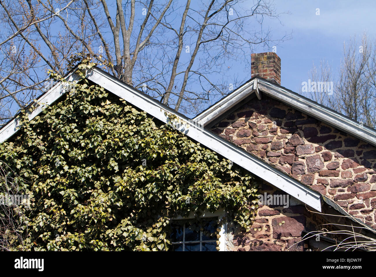 The gable end of a country cottage with ceder shakes stone chimney and ...