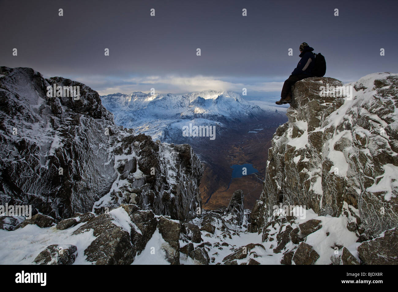 A hill walker rests on a snow covered Blaven (Blabheinn) looking ...