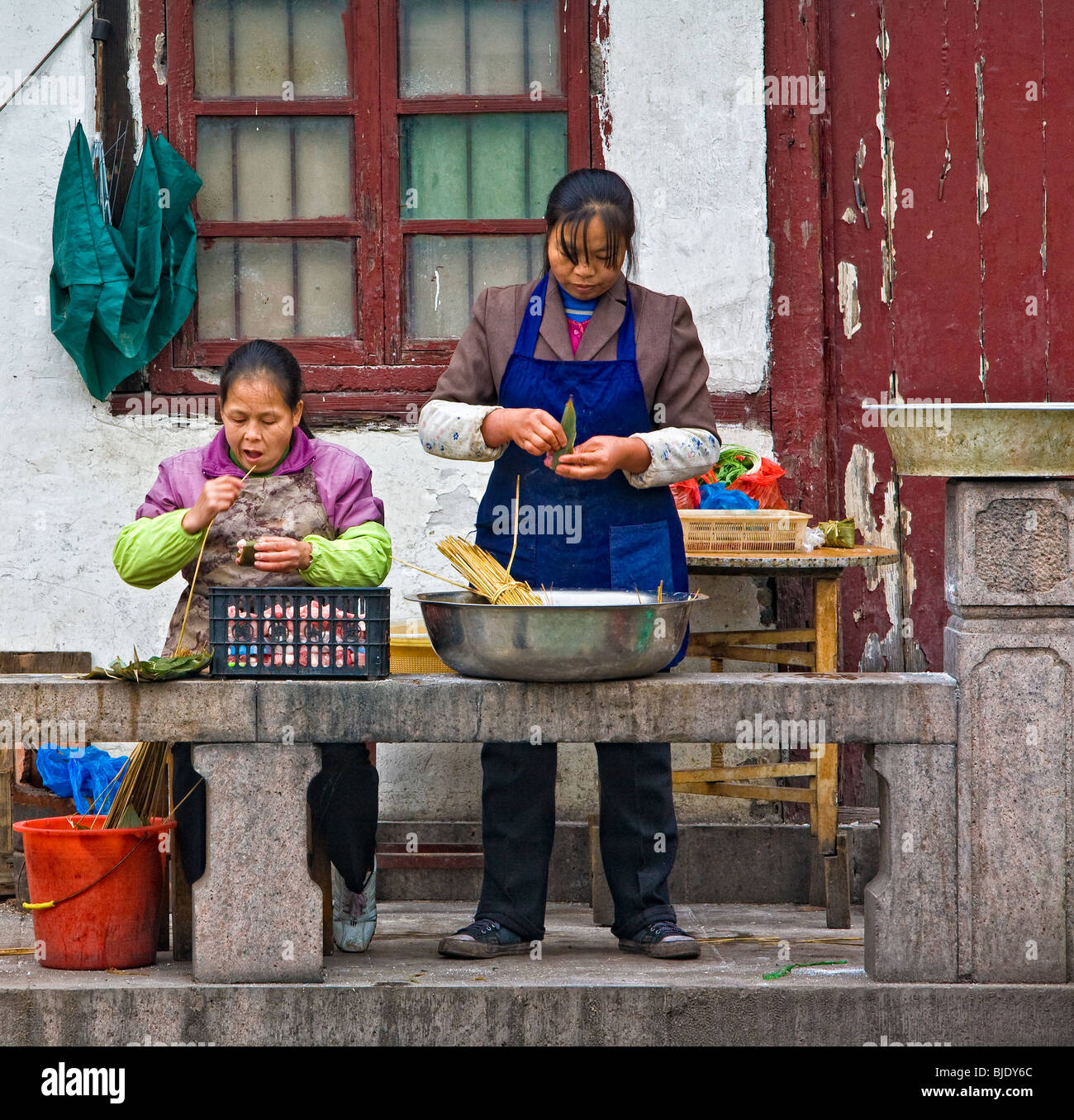 Two Chinese women making rice cakes in front of home Stock Photo - Alamy