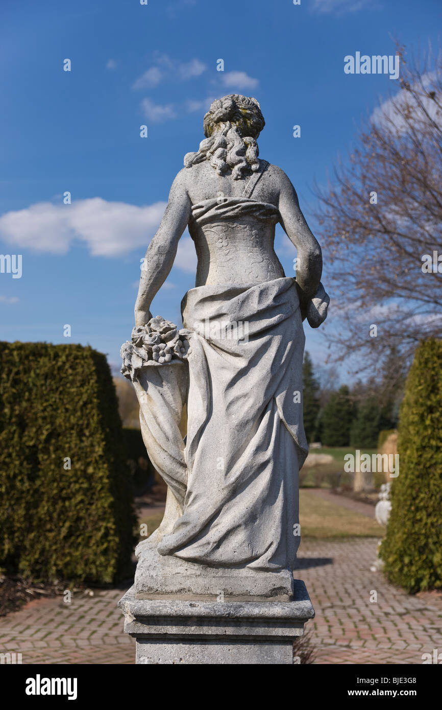 Back view of a classical public sculpture of a woman in a garden park ...