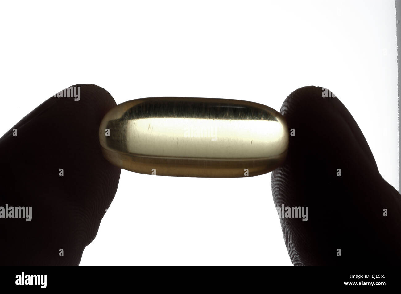 Man holding a (cod liver oil) capsule Stock Photo - Alamy