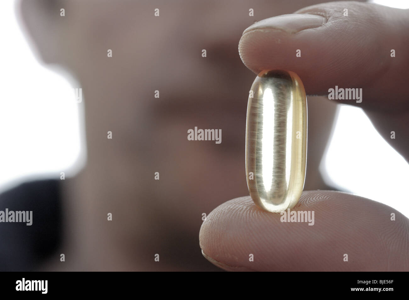 Man holding a (cod liver oil) capsule Stock Photo - Alamy