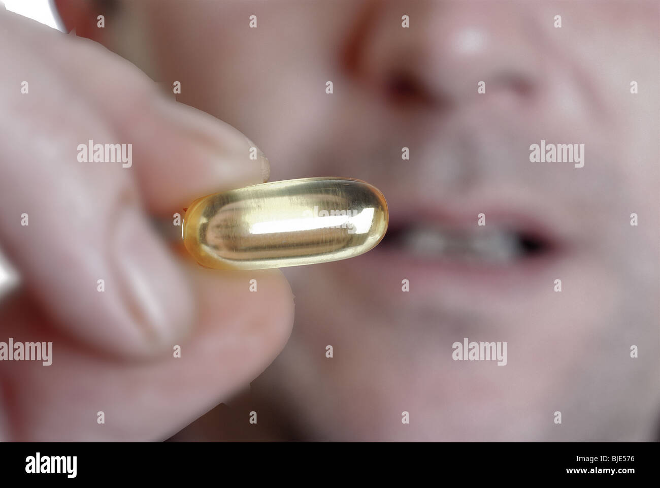 Man holding a (cod liver oil) capsule Stock Photo - Alamy