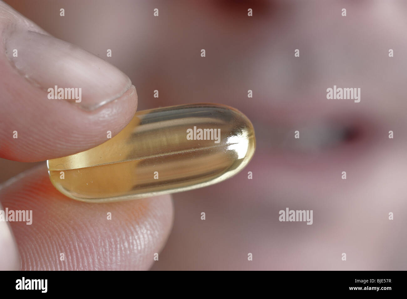 Man holding a (cod liver oil) capsule Stock Photo - Alamy