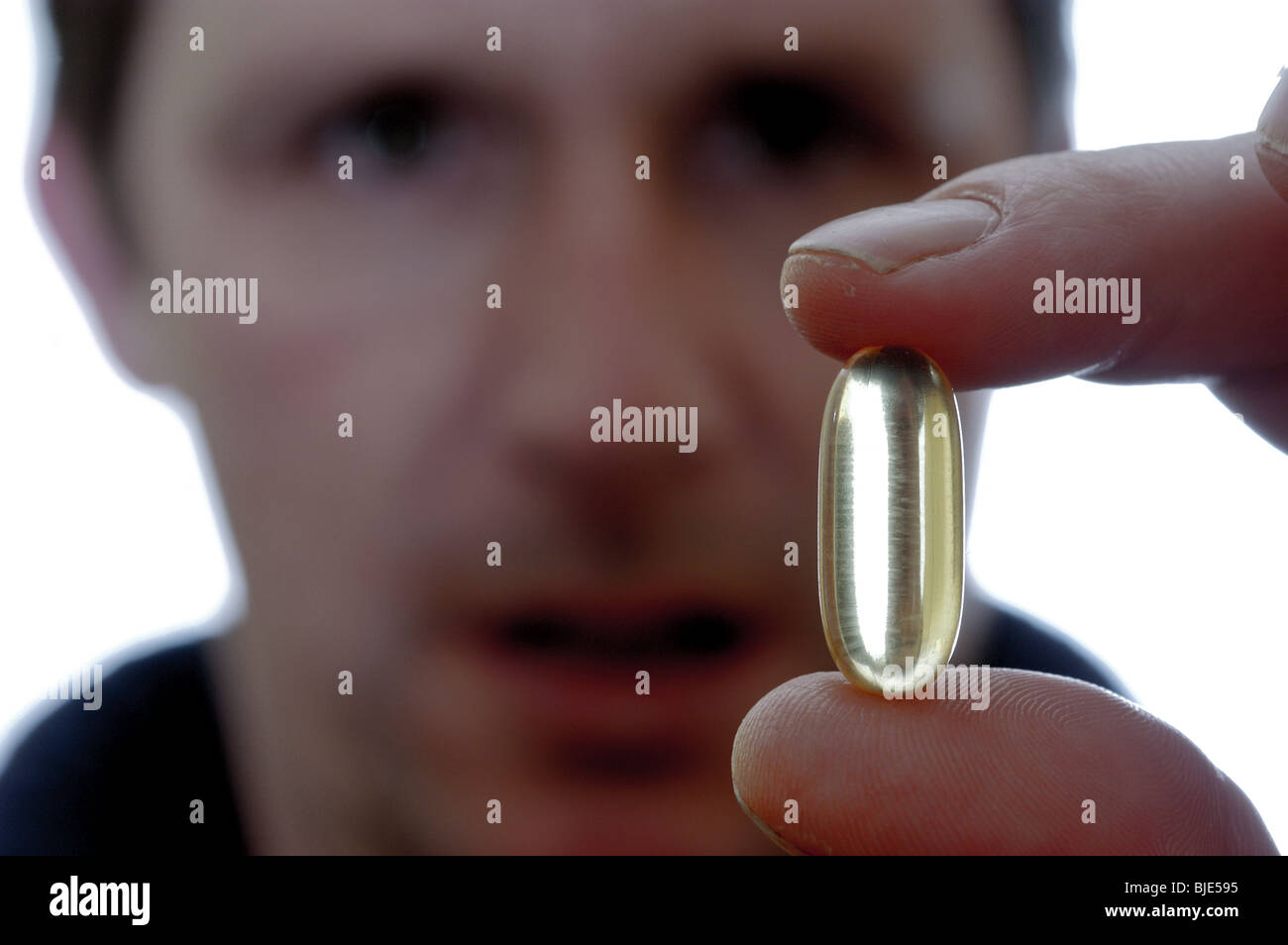 Man holding a (cod liver oil) capsule Stock Photo - Alamy