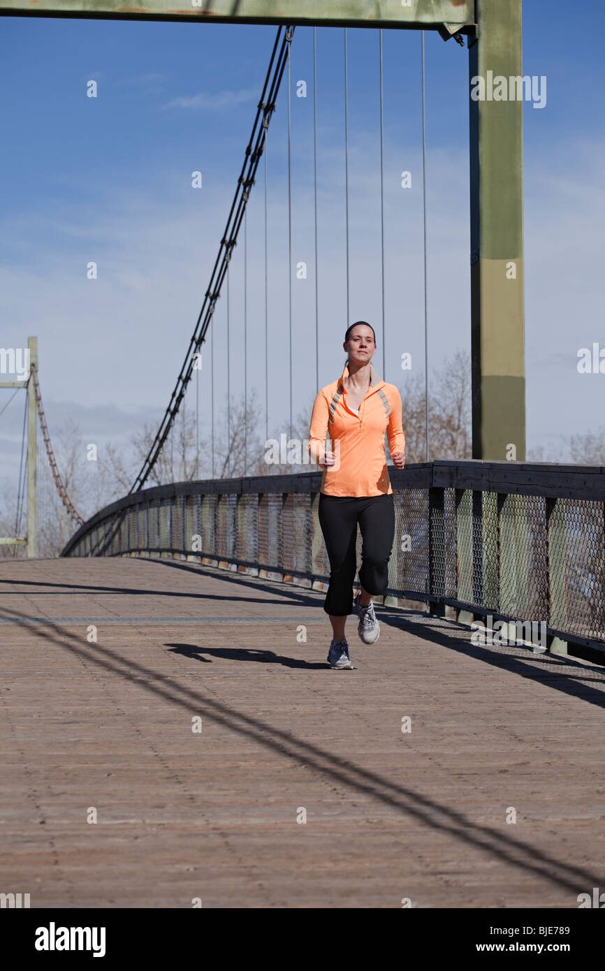 Woman running across bridge Stock Photo - Alamy
