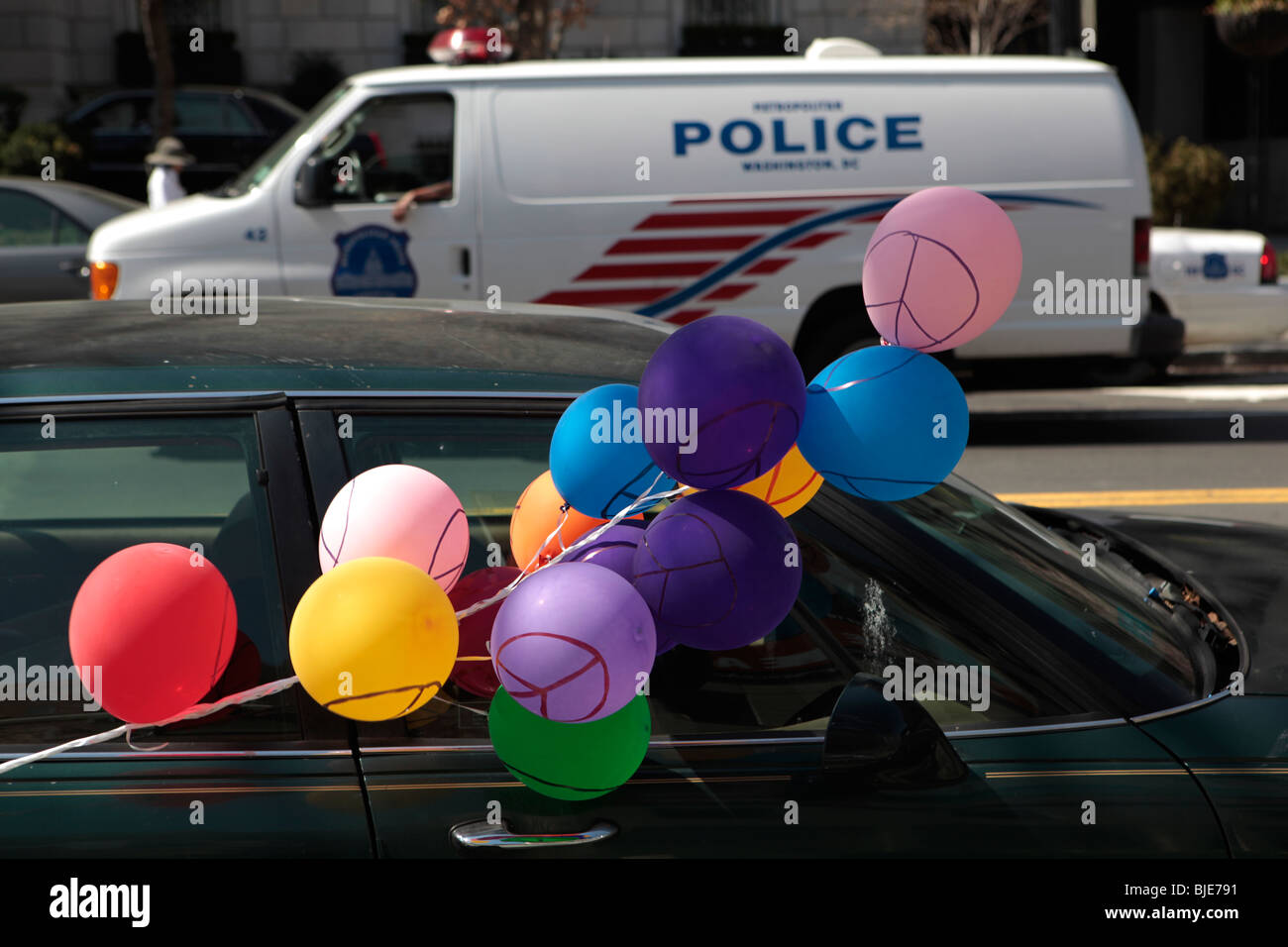 Peace balloons attached to car with D.C. Metro Police Van in background ...