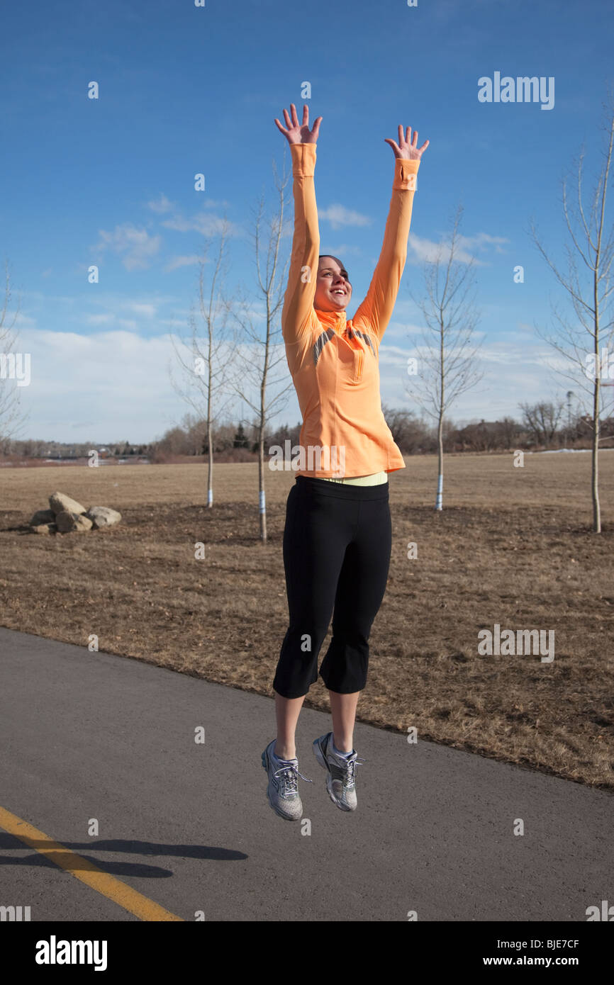 Woman jumping for joy while exercising outside in city park Stock Photo ...