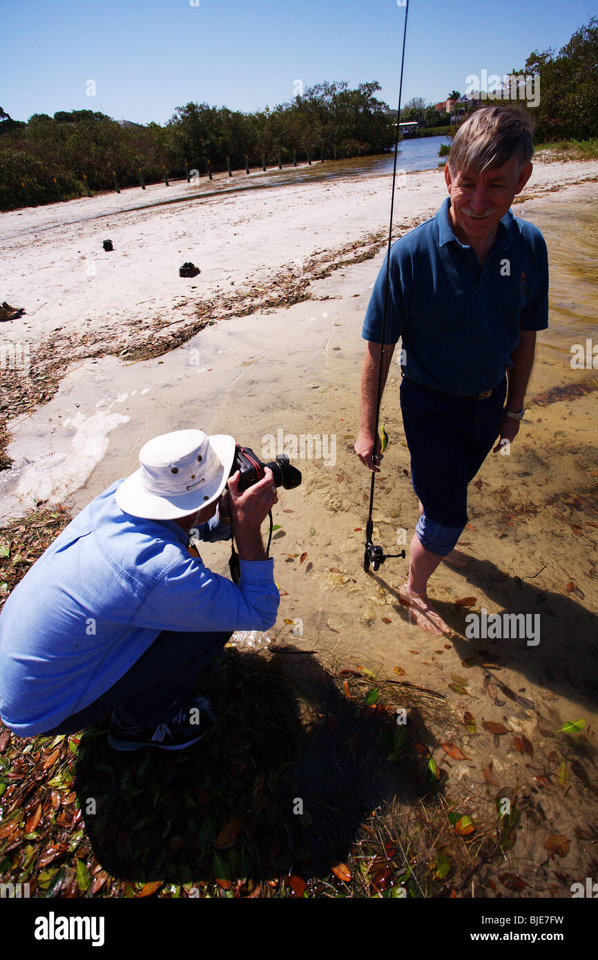 LEGS OF FISHERMAN STANDING IN SHALLOW WATER HOLDING FISHING ROD AND ...