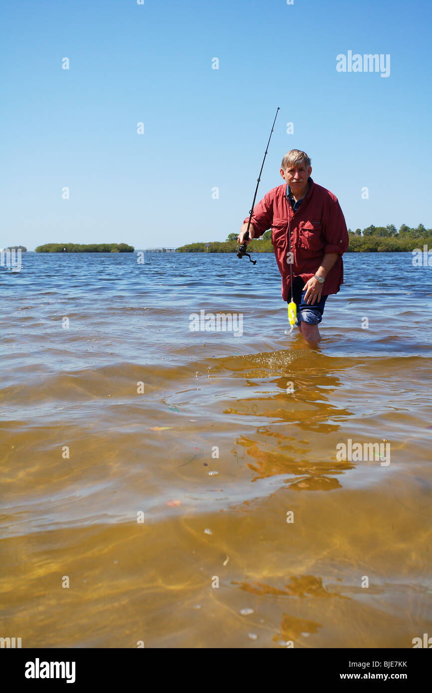 FISHERMAN WADING IN SHALLOW WATER CASTING TOP WATER BAIT RED SHIRT ...