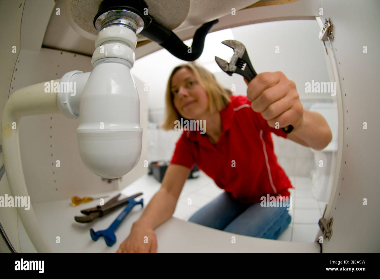 Female plumber working under sink Stock Photo - Alamy